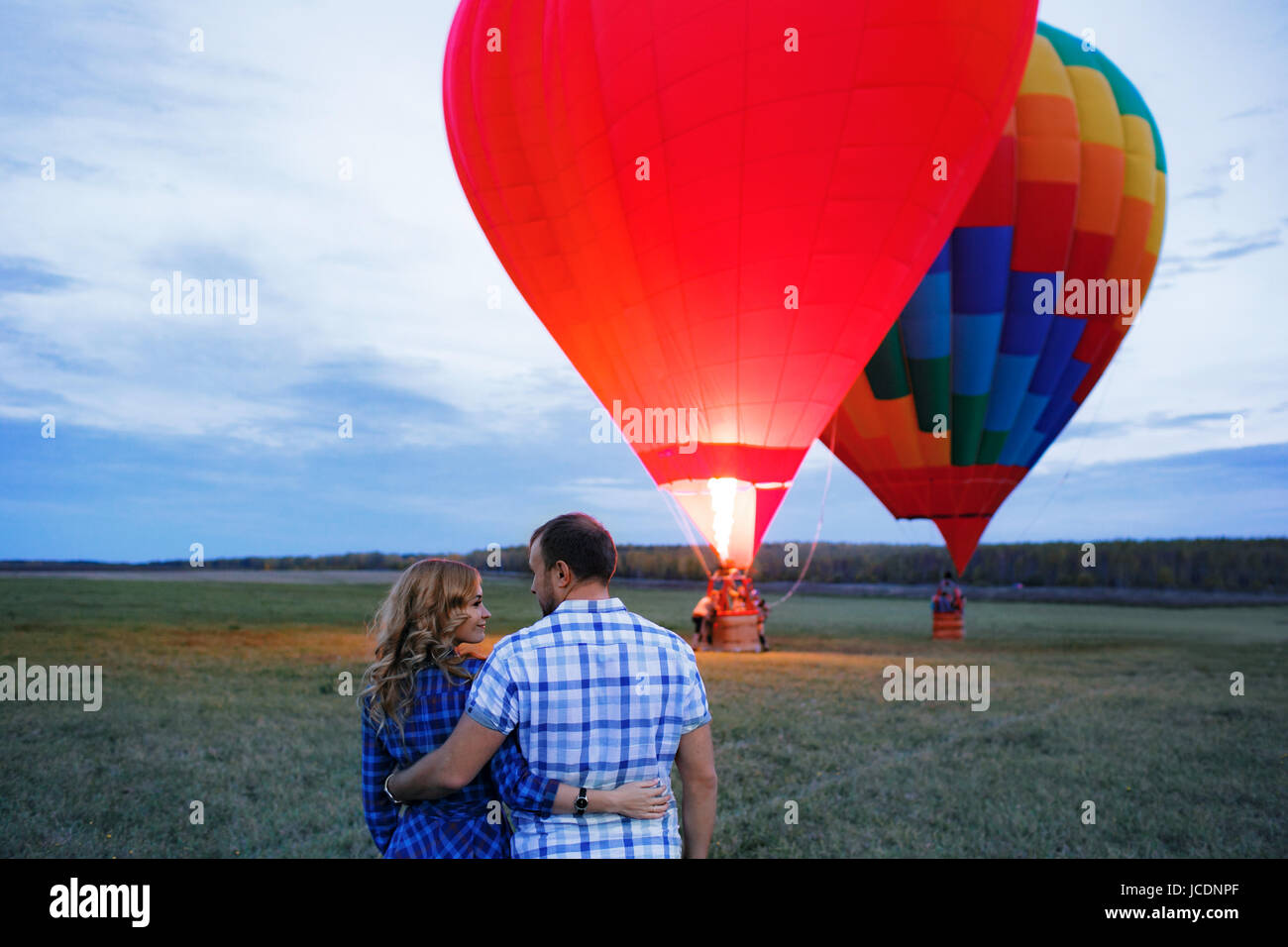 Beautiful romantic couple hugging at meadow. hot air balloon on a ...