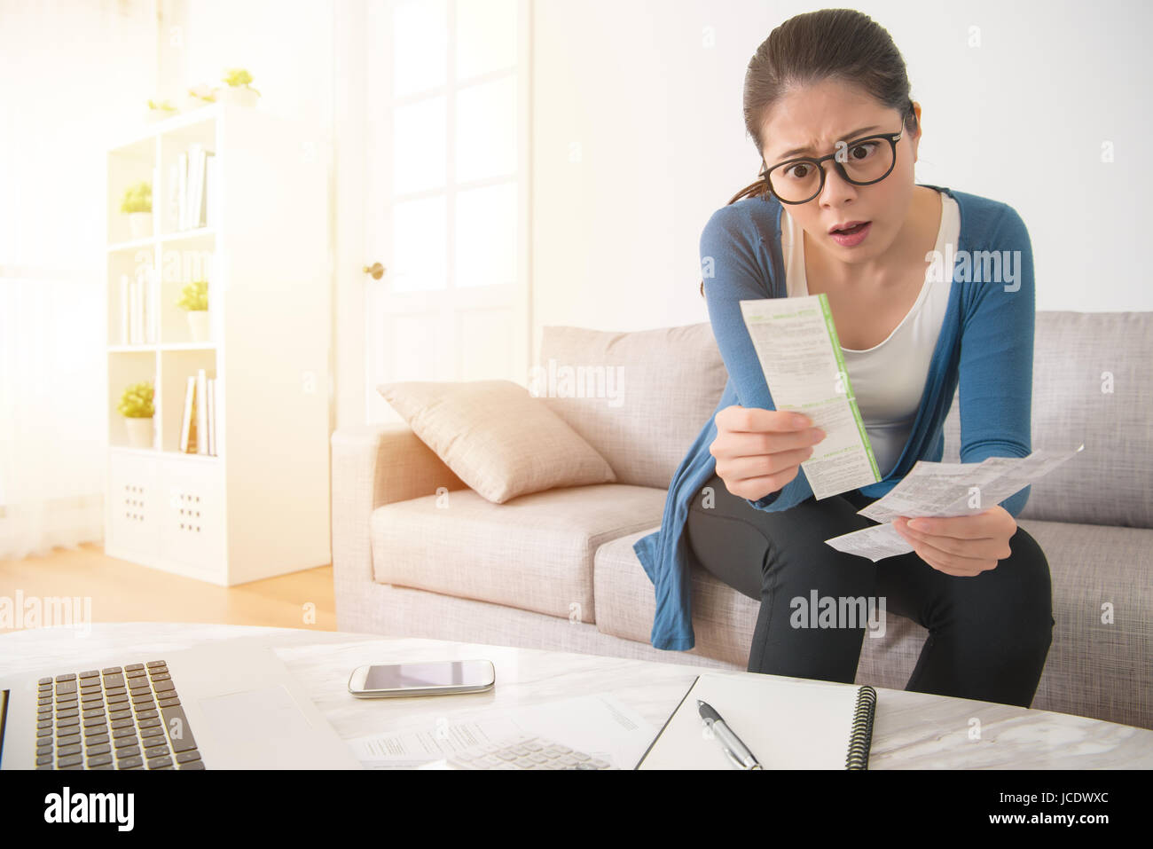 beautiful girl stressed over bills. surprised young woman using ...