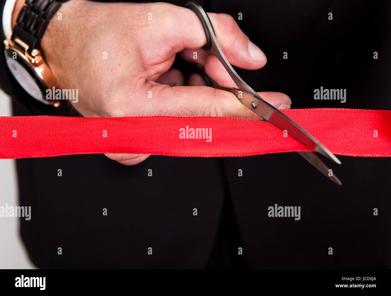 Businessman cutting a red tape against white background Stock Photo - Alamy