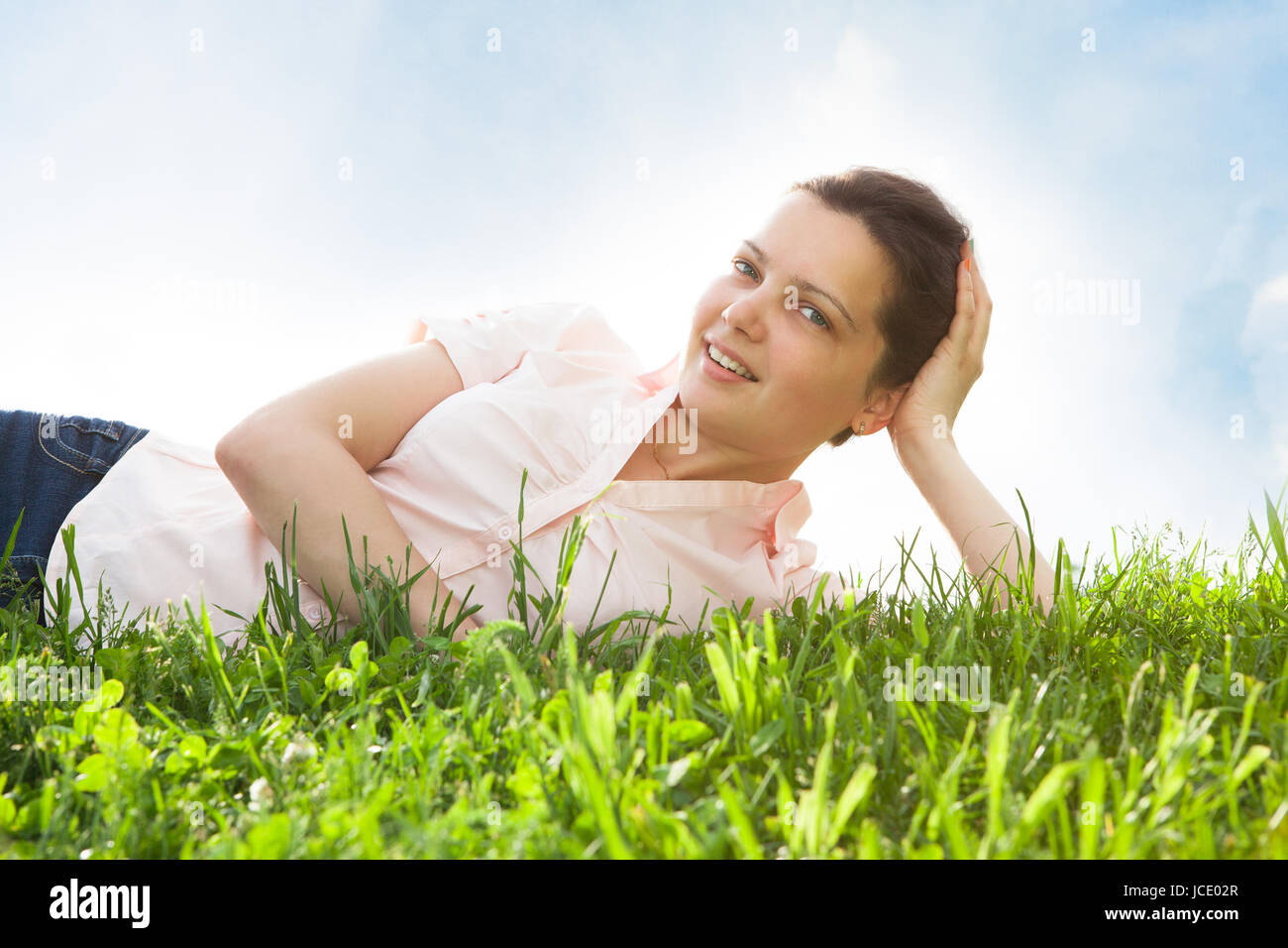Portrait Of Young Woman Relaxing In Grassland Stock Photo - Alamy