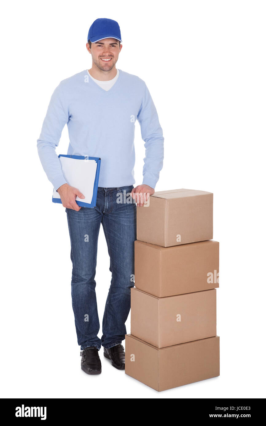Smiling young delivery man holding stack of boxes. Isolated on white ...
