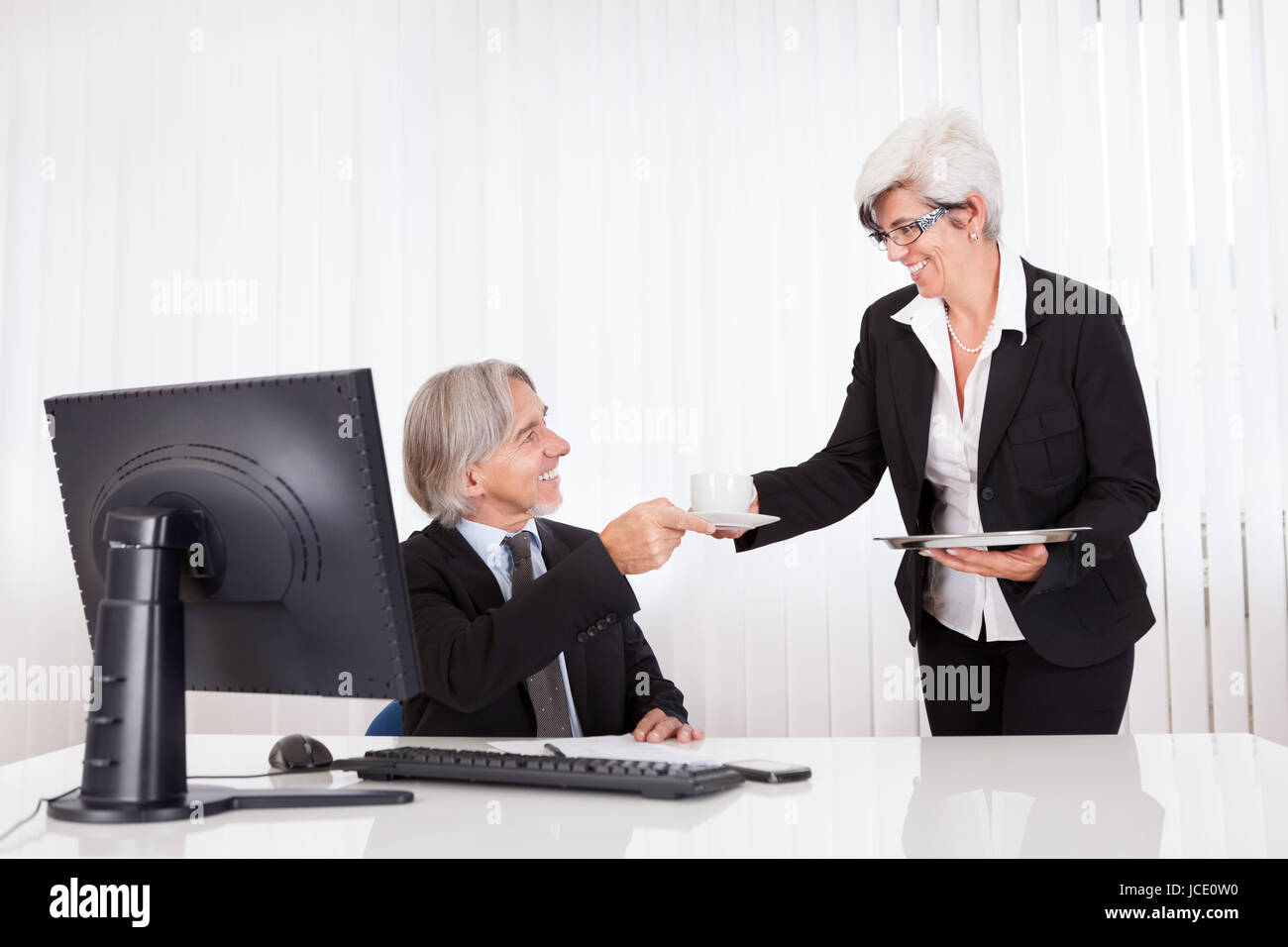Smiling secretary or co-worker bringing a welcome cup of tea for the ...