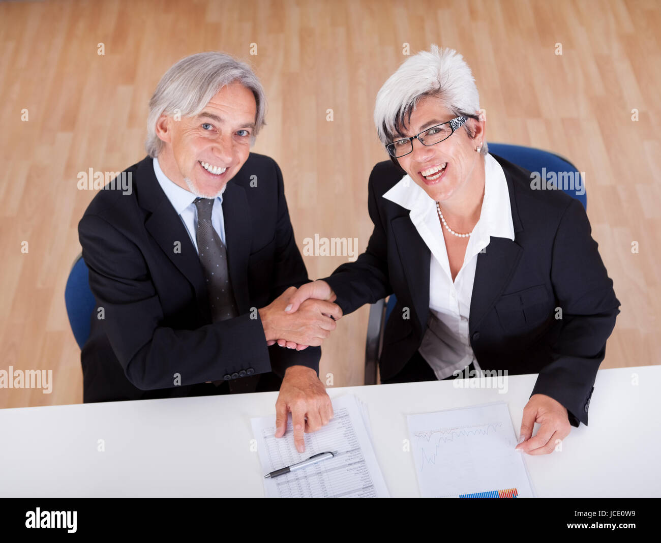Overhead view of business handshake sealing a deal between two smiling ...