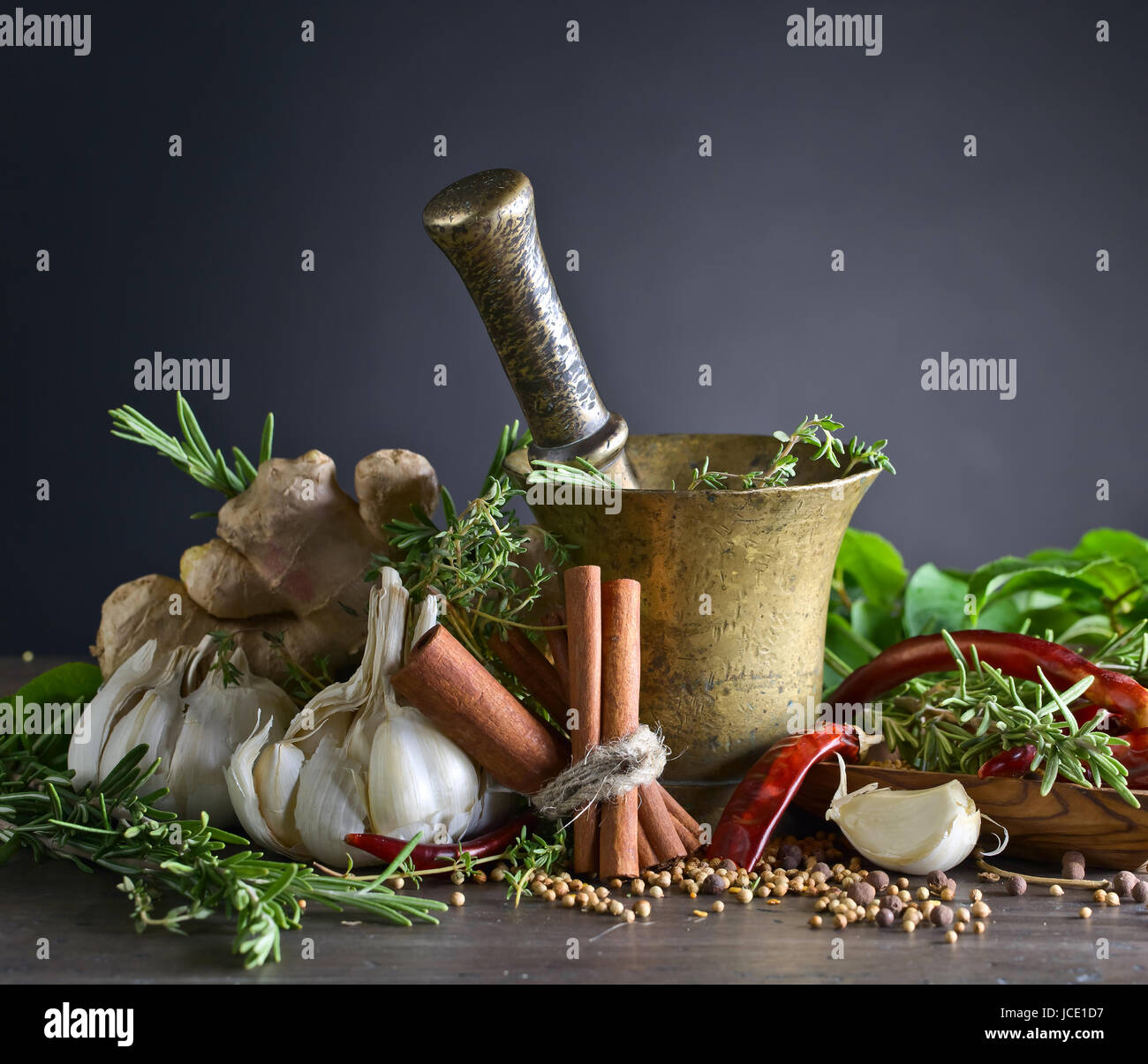 Different herbs and spices on a wooden table . Old copper mortar with ...