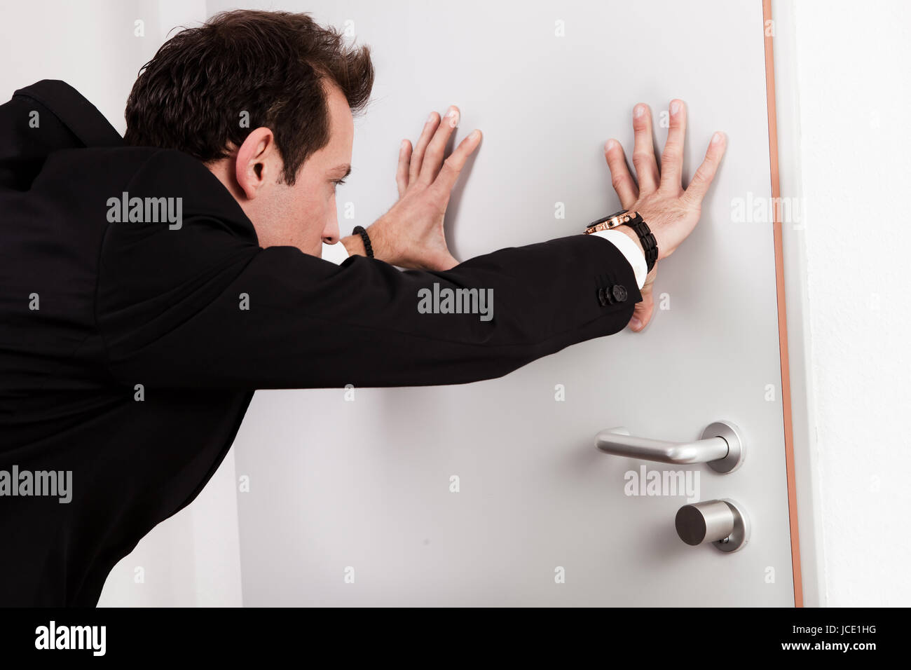 Businessman pushing the door to prevent people entering room Stock ...