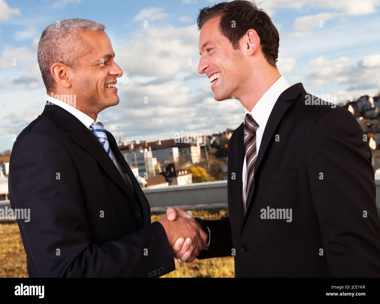 Two handsome businessmen handshaking hi-res stock photography and ...
