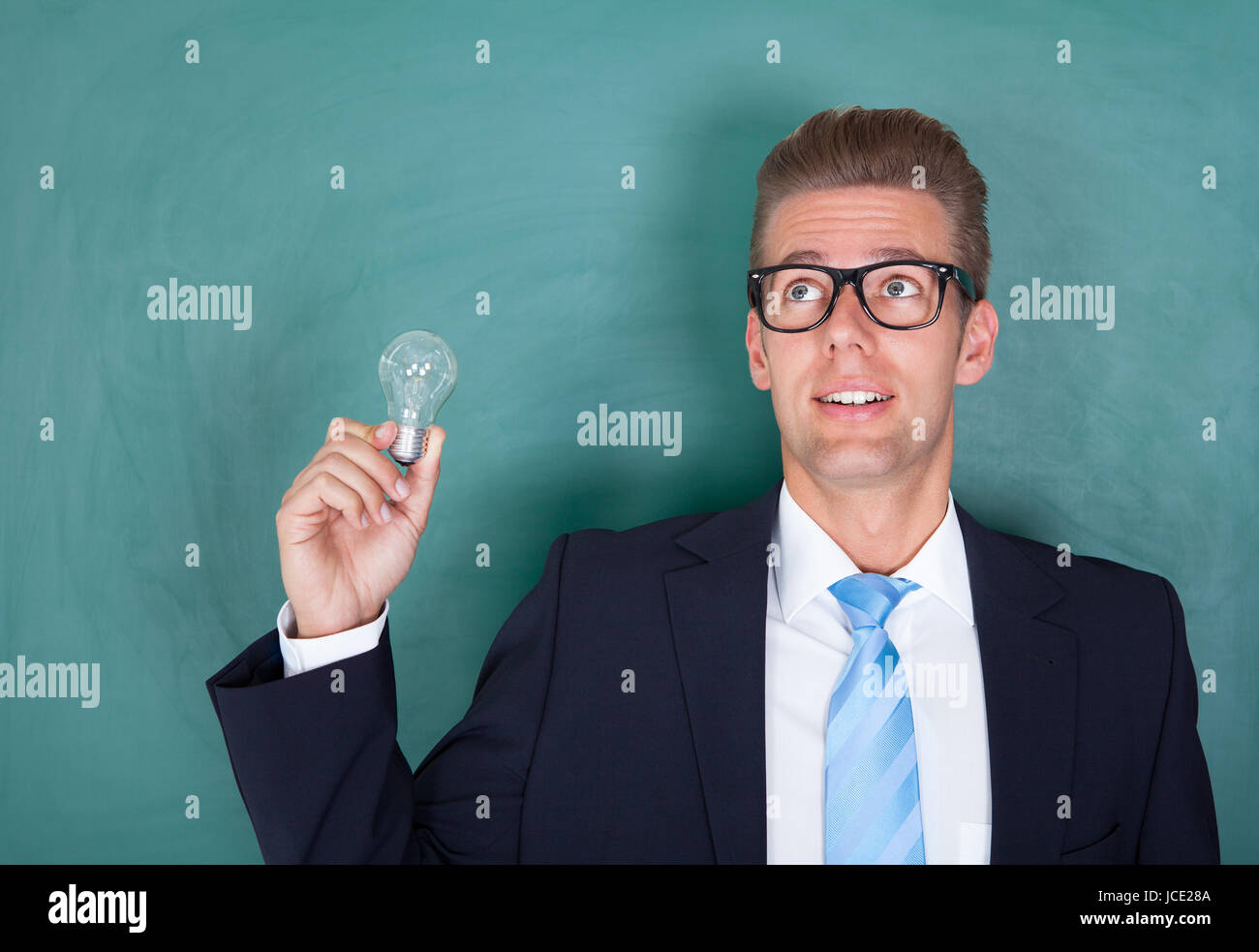 Young Male Professor Holding Light Bulb Against Chalkboard Stock Photo ...