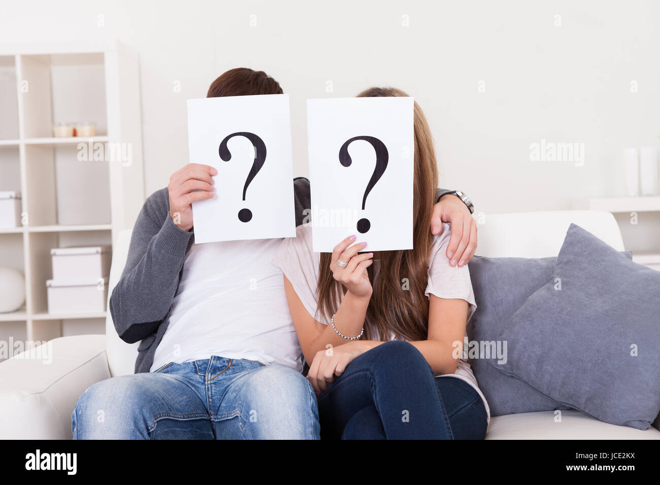 Couple in the living room with question marks in front of their faces ...