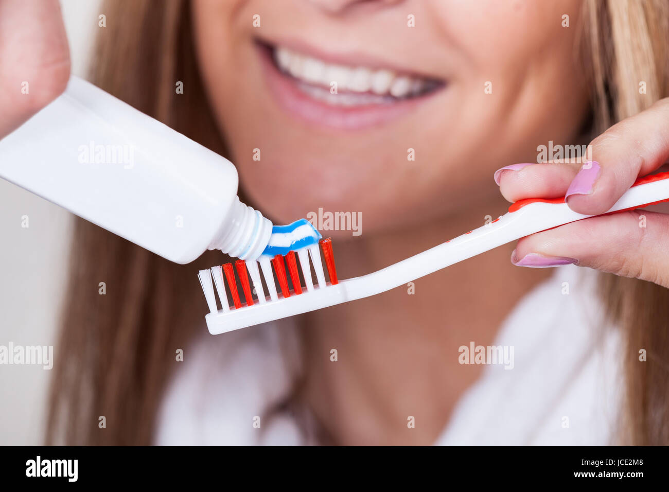 Mom put blue striped toothpaste on red & white toothbrush Stock Photo ...