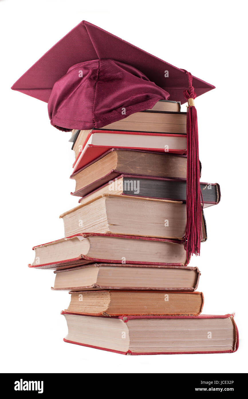 graduation cap on the top of a pile of old books isolated on white ...