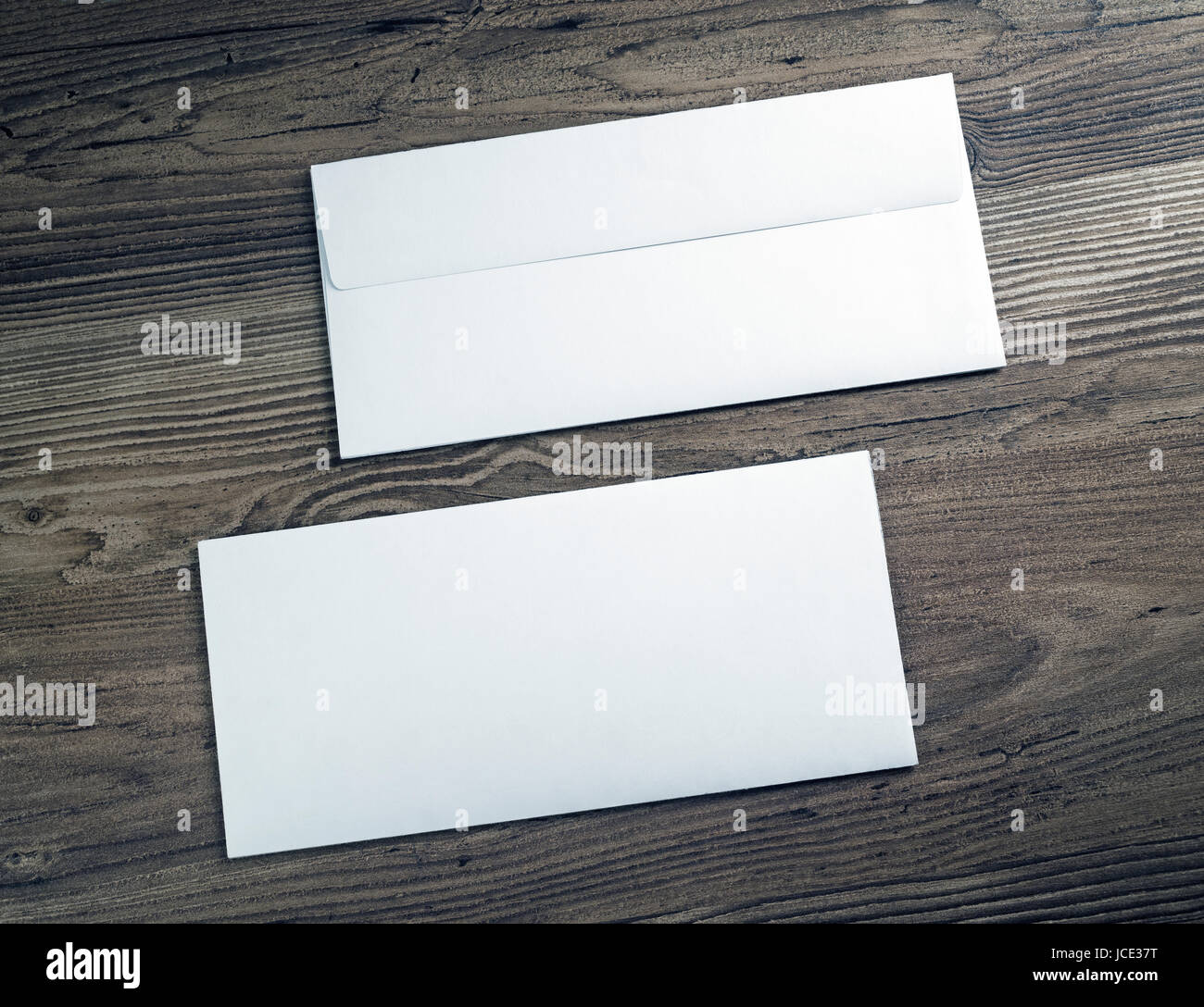 Two white blank envelopes on wooden background. Front and back side ...
