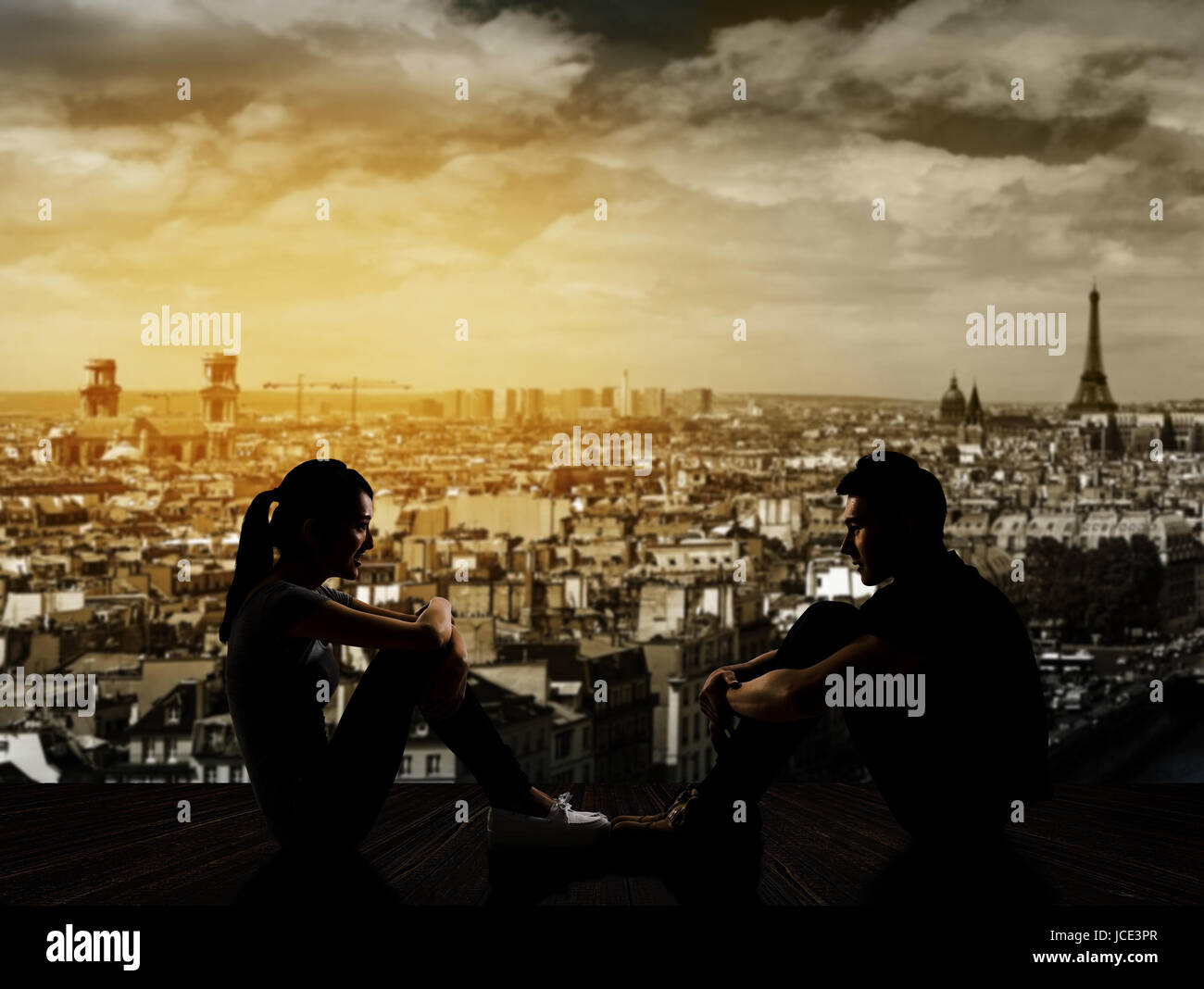 Silhouette of young couple face to face sit on ground in the city night ...