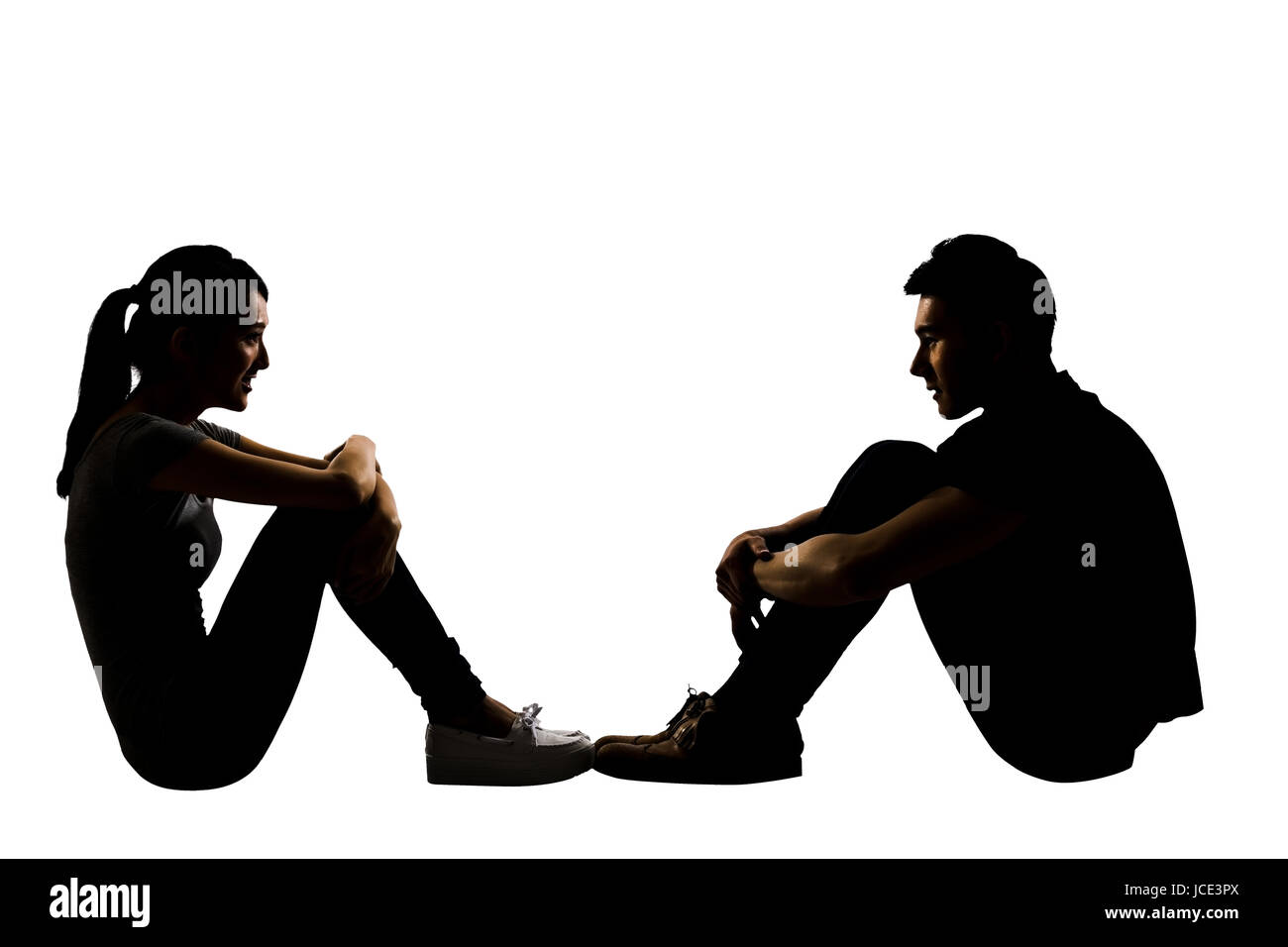 Young couple face to face sit on ground, full length portrait isolated ...