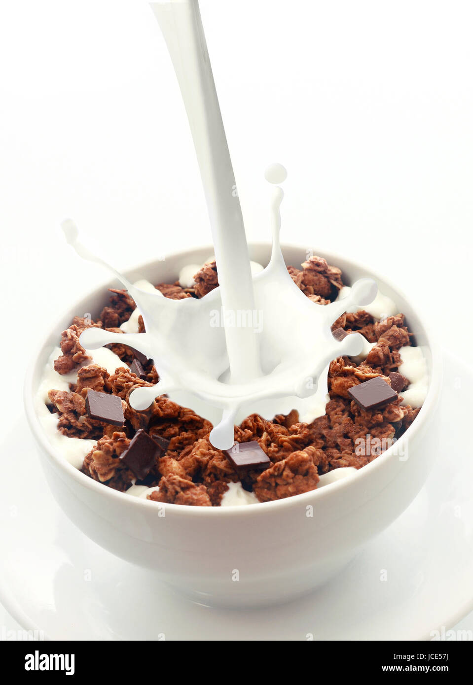 Pouring milk with a splash of droplets into a bowl of crunchy choc chip ...