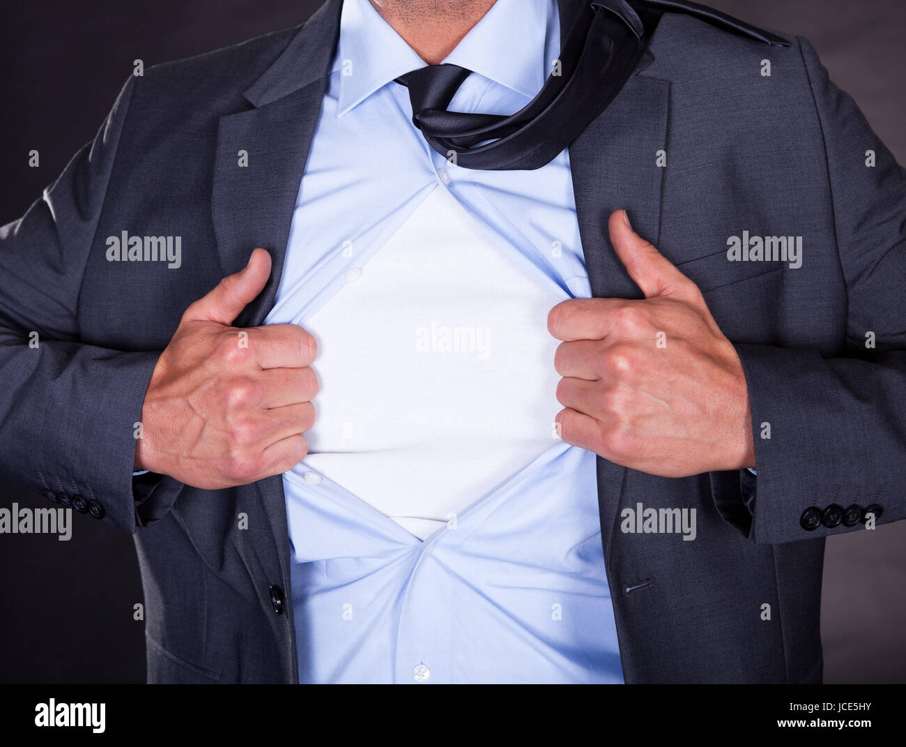 Superhero Tearing Off His Shirt On Black Background Stock Photo - Alamy