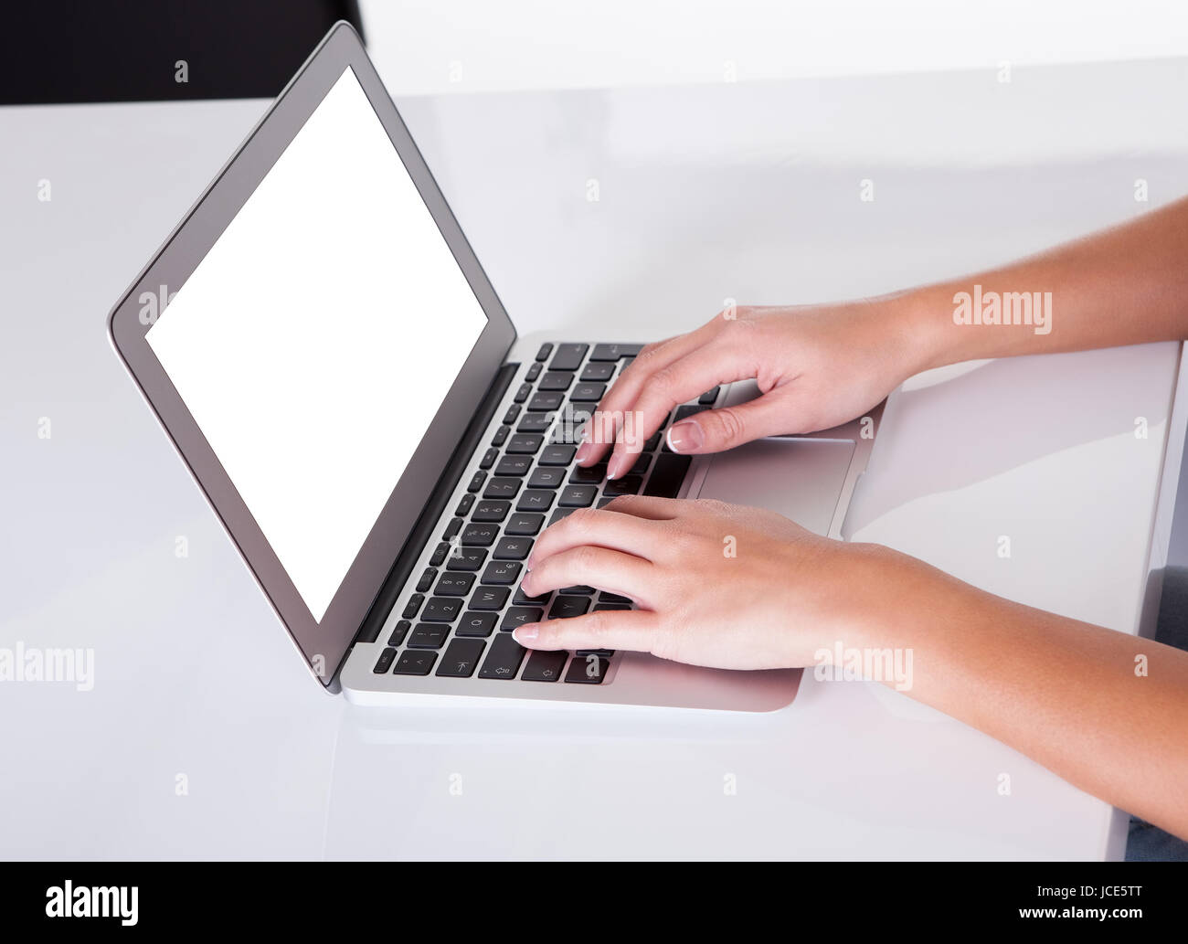 High angle cropped view image of female hands typing on a laptop keyboard with a blank white ...