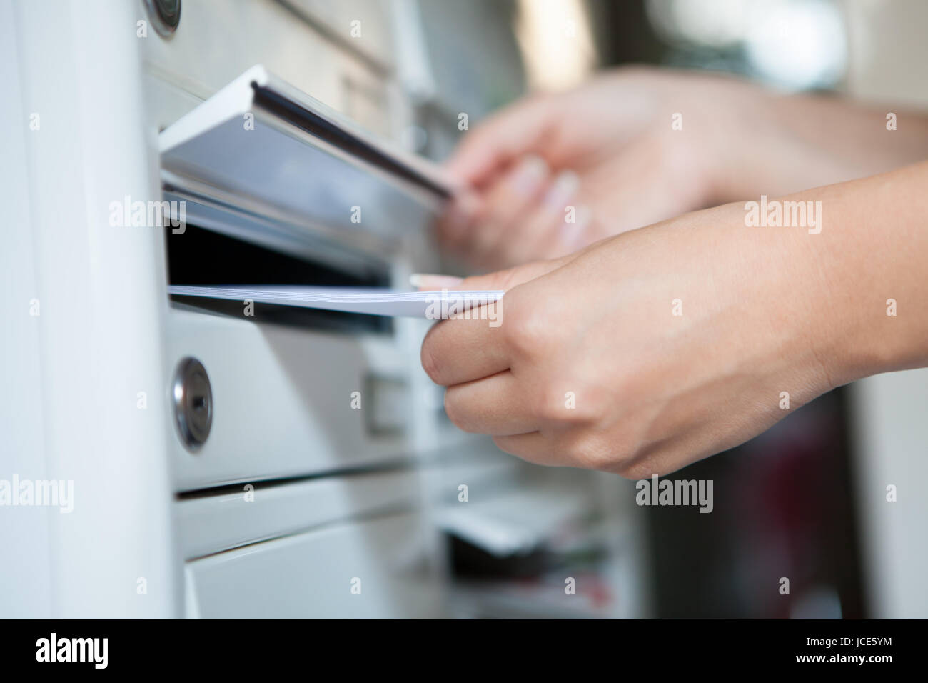 Close-up of woman's hand holding envelope and inserting in mailbox ...