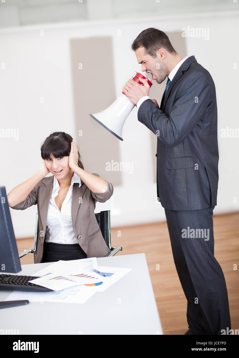 Angry businessman screaming at employee at the office in megaphone ...
