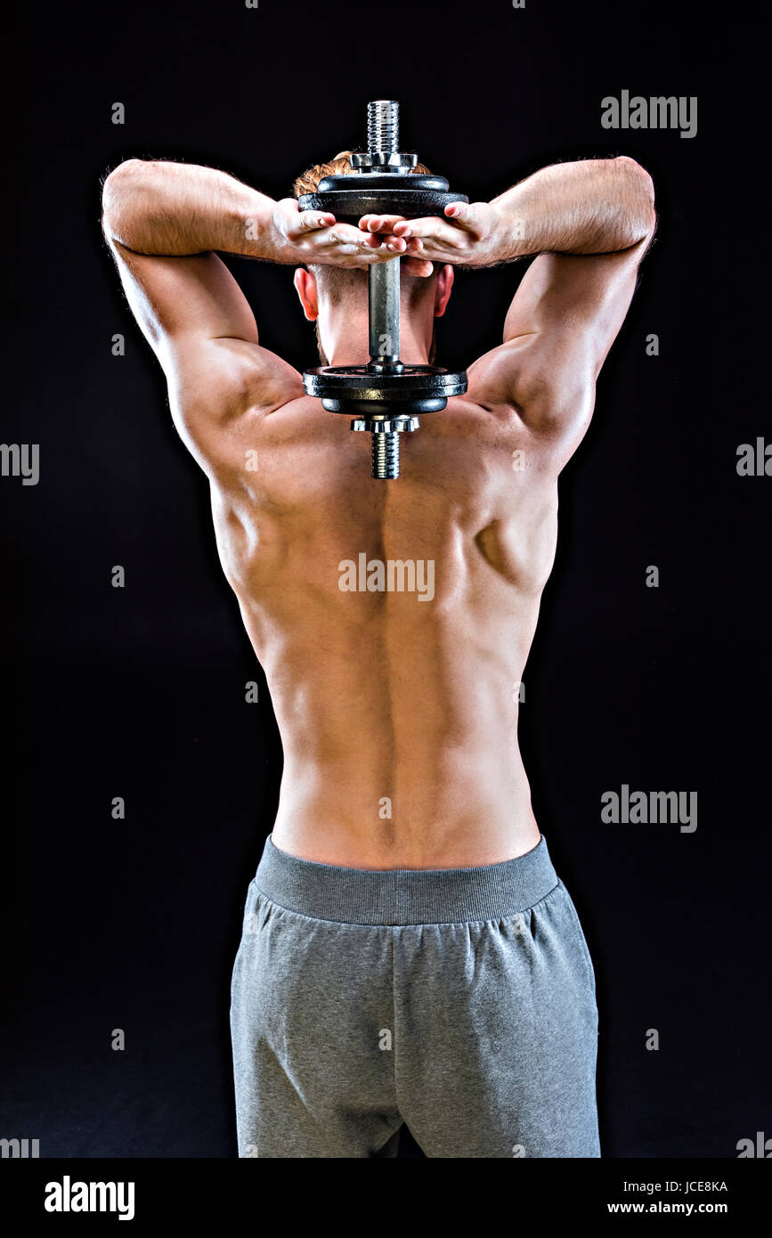 back view of bodybuilder training with dumbbell isolated on black Stock ...