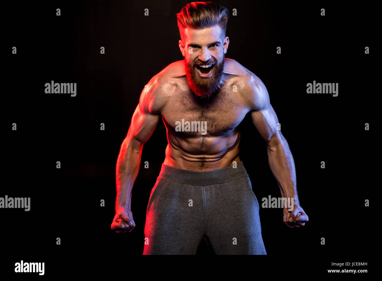 handsome bodybuilder gesturing and yelling isolated on black with ...