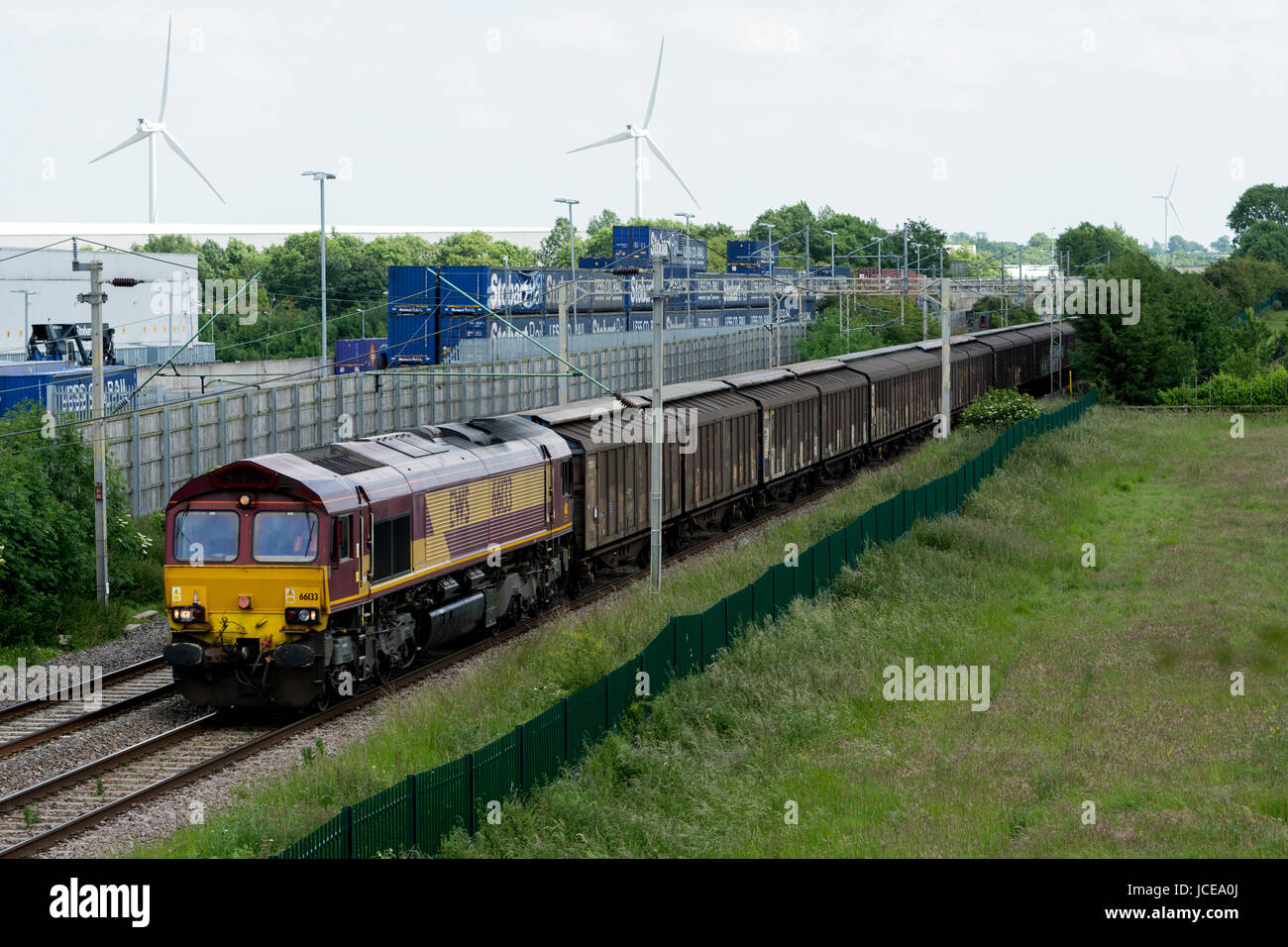 Class 66 diesel locomotive pulling a freight train past Tesco warehouse ...