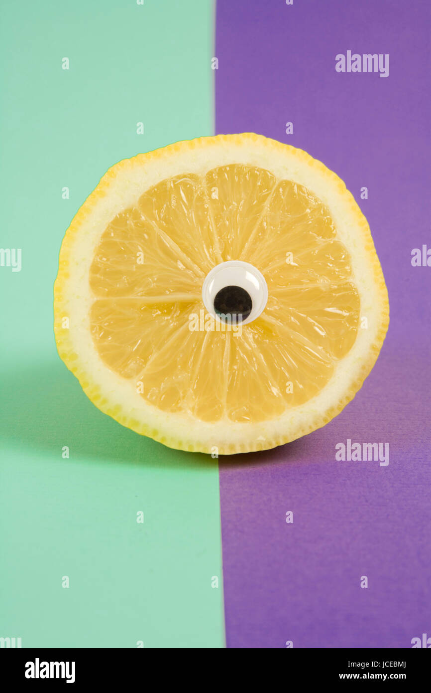 Minimal still life photography.An lemon cut in half and wearing doll's ...