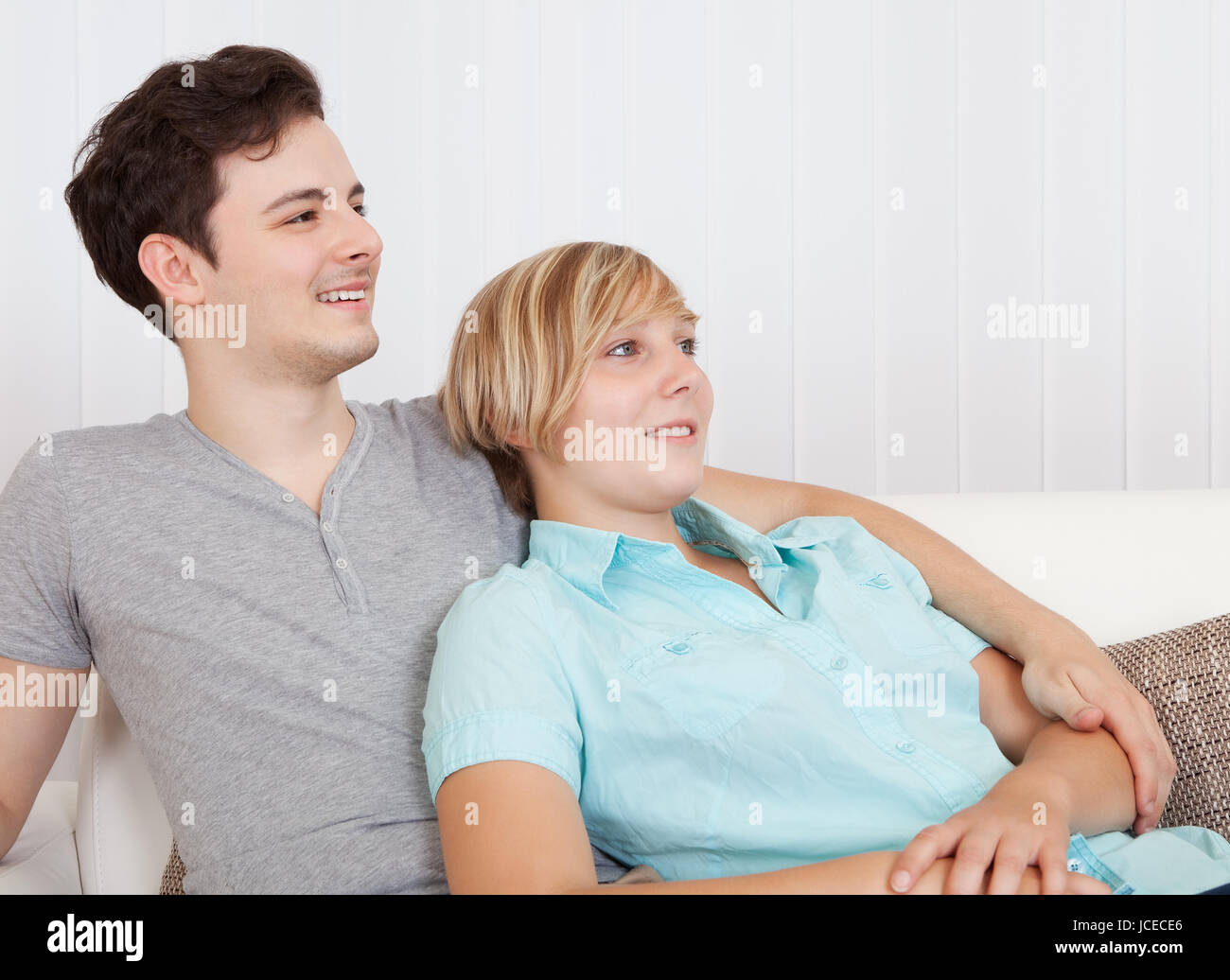 Smiling loving attractive young couple sitting close together relaxing ...