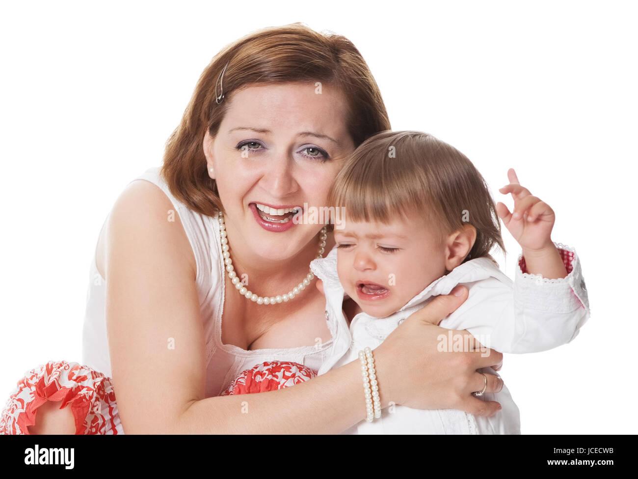 Young baby who is upset and crying being cuddled in its mothers arms as ...