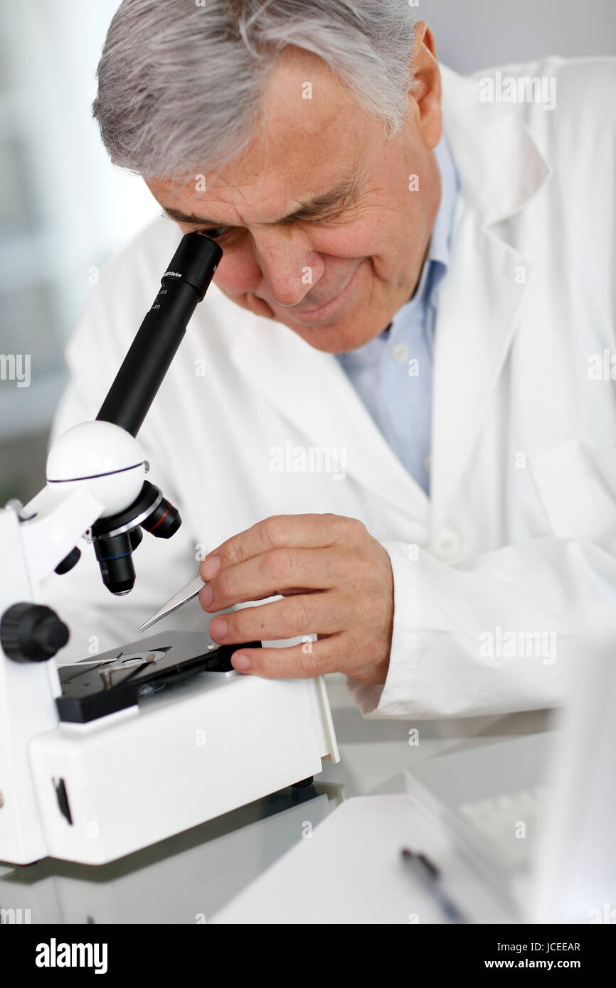 Scientist in lab looking through microscope lens Stock Photo - Alamy