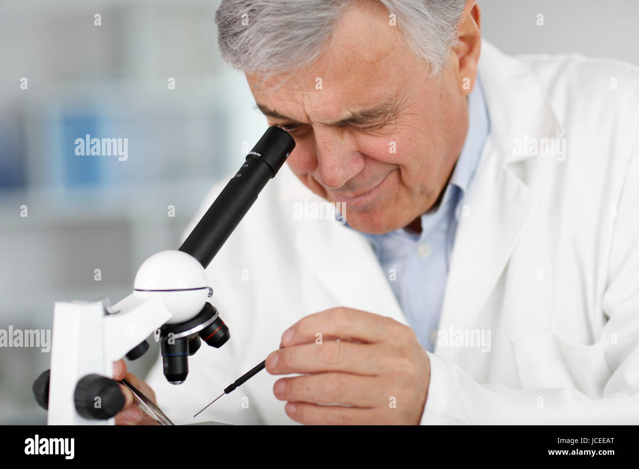 Scientist in lab looking through microscope lens Stock Photo - Alamy