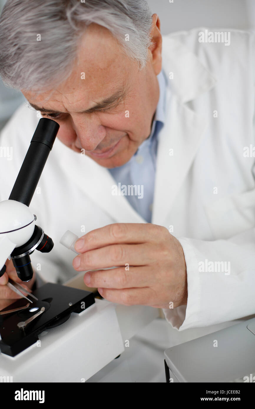 Scientist in lab looking through microscope lens Stock Photo - Alamy