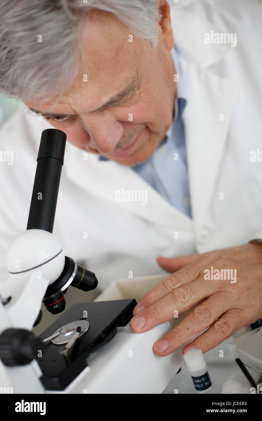 Scientist in lab looking through microscope lens Stock Photo - Alamy