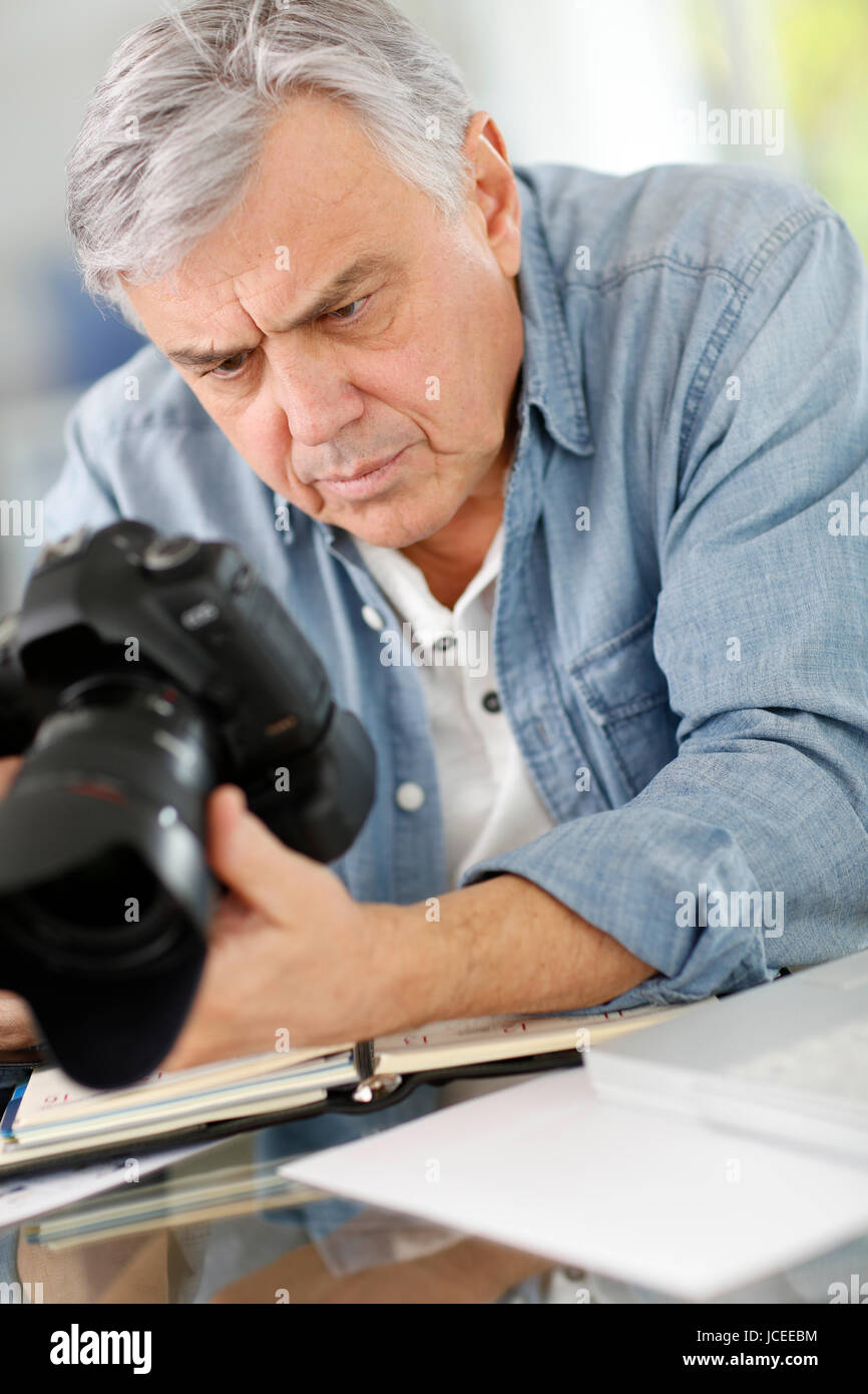 Photographer in office looking at camera screen Stock Photo - Alamy