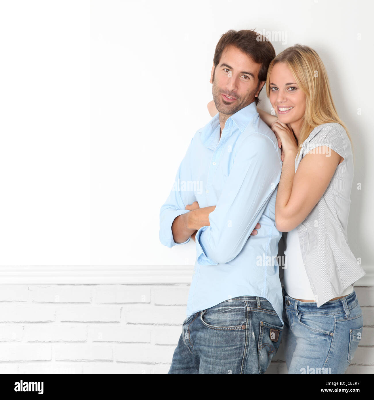 Young couple standing on white wall Stock Photo - Alamy