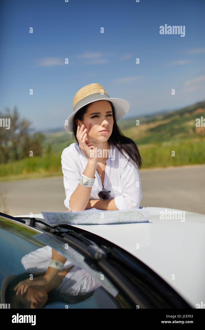 A tourist with a map at the car checks the route to the destination ...