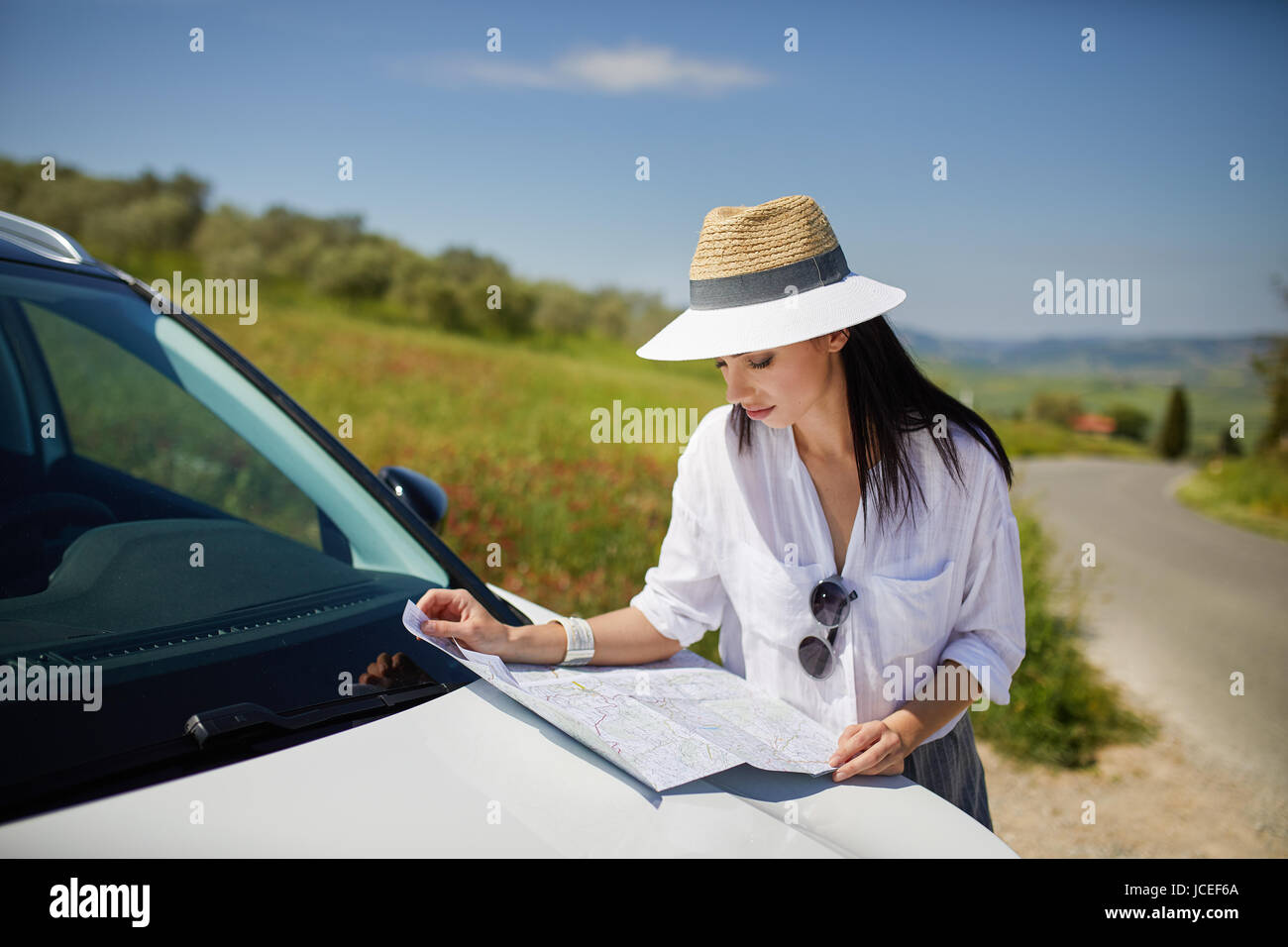 A tourist with a map at the car checks the route to the destination ...