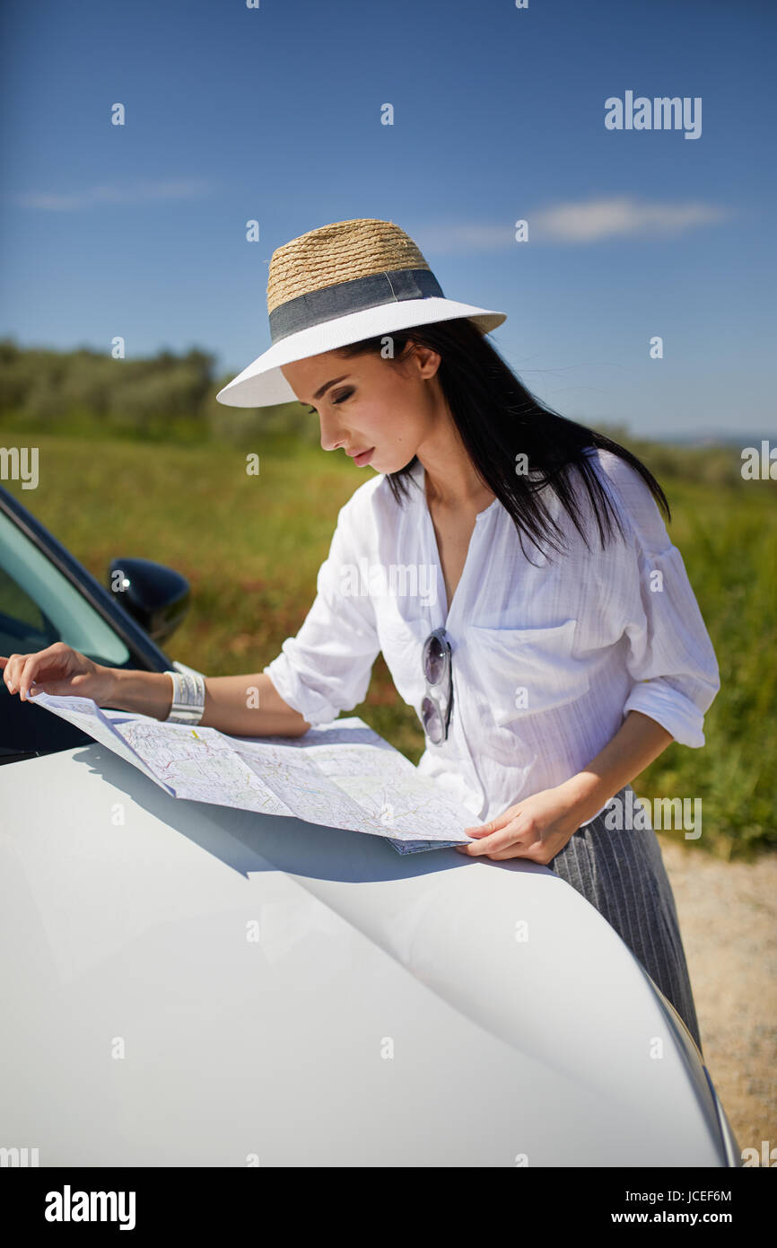 A tourist with a map at the car checks the route to the destination ...