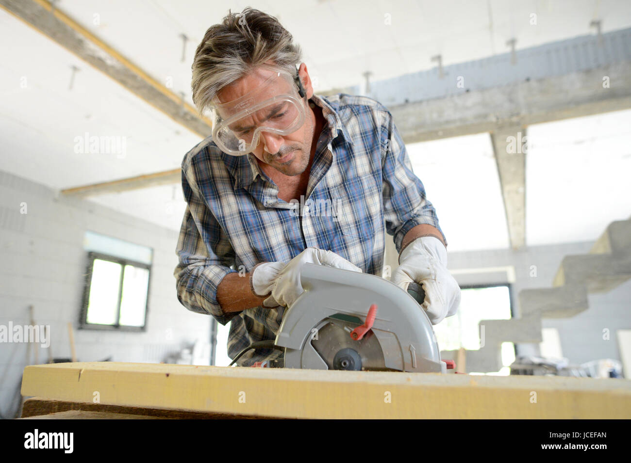 Man using electric saw inside house under construction Stock Photo - Alamy