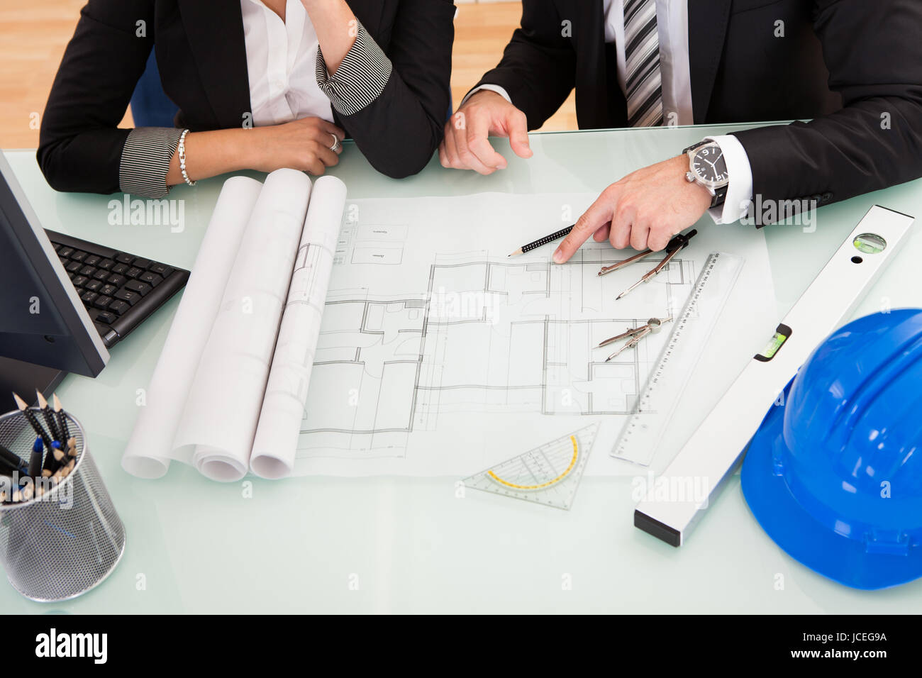 Cropped overhead view of a male and female architect discussing a set ...