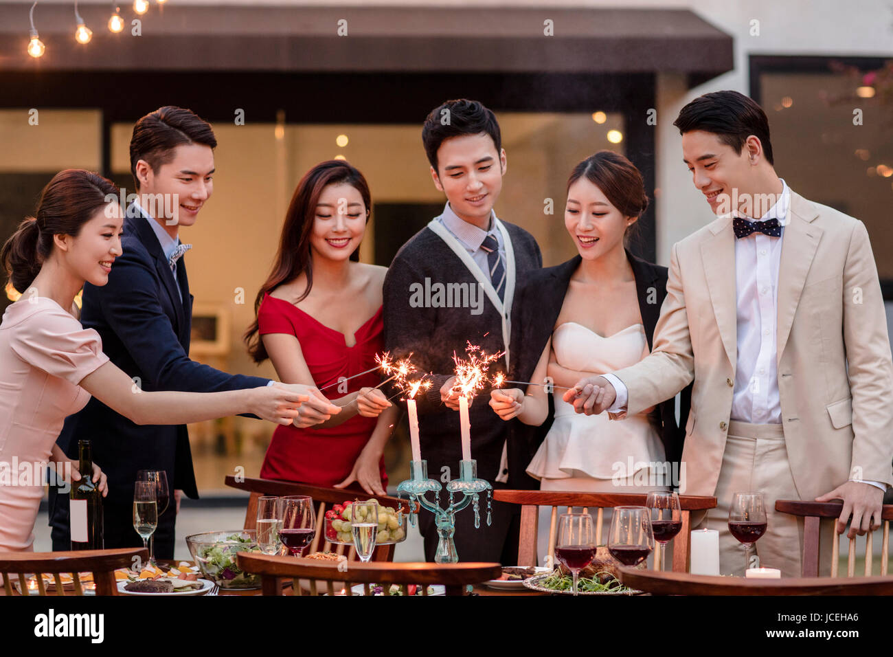Smiling people with firecrackers at party Stock Photo - Alamy
