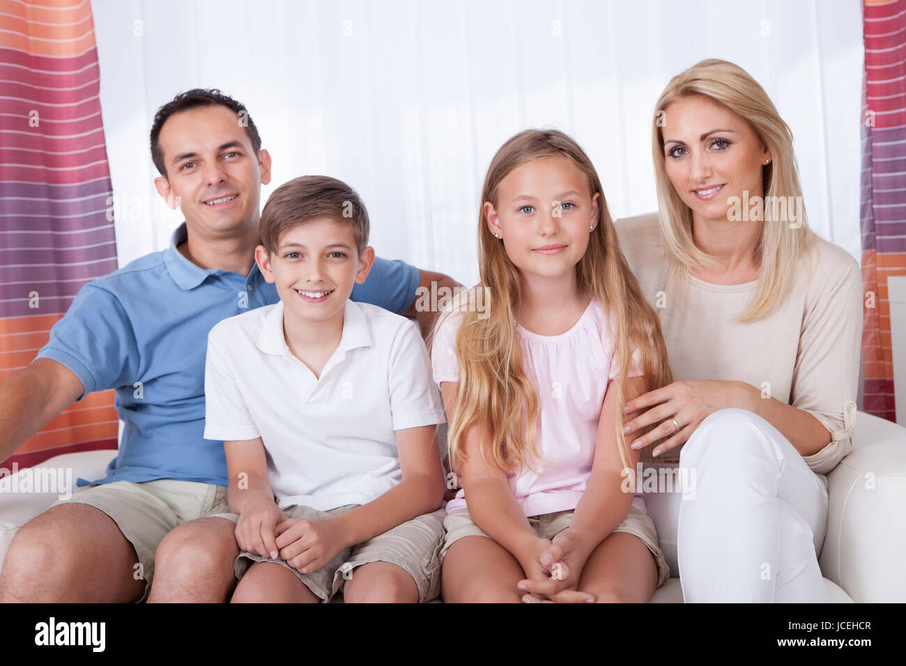 A Happy Family With Two Children Sitting On Sofa At Home Stock Photo ...