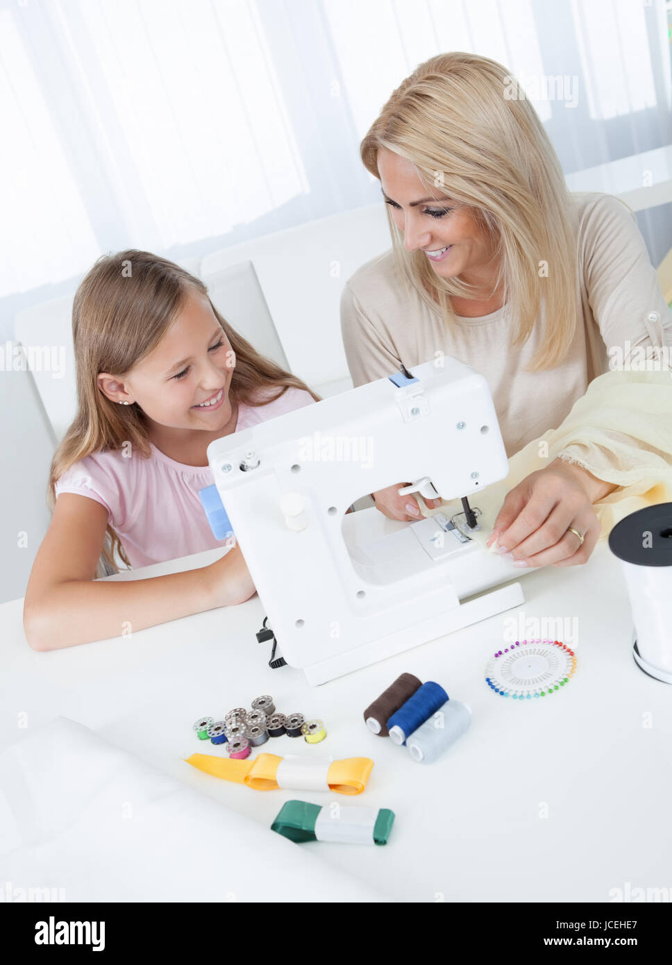 Portrait Of A Beautiful Young Girl Sewing With Her Mother At Home Stock ...
