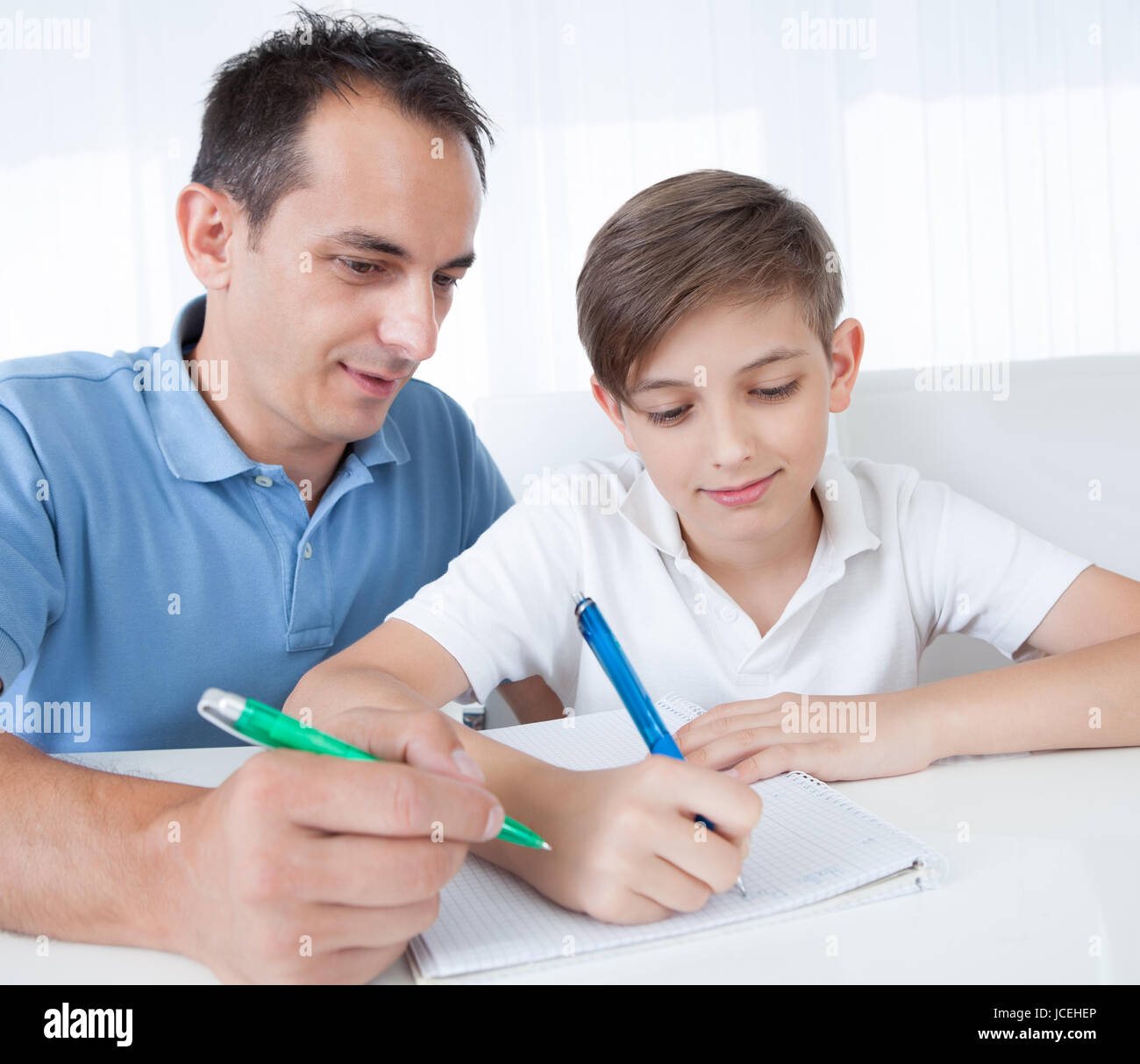 Portrait Of Father And Son Doing Homework At Home Stock Photo - Alamy