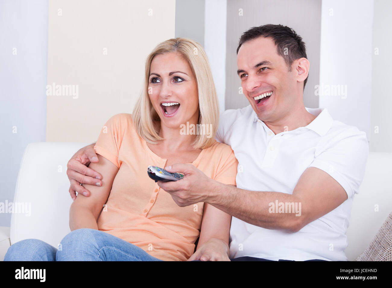 Happy Couple Holding Remote And Watching Television Stock Photo - Alamy