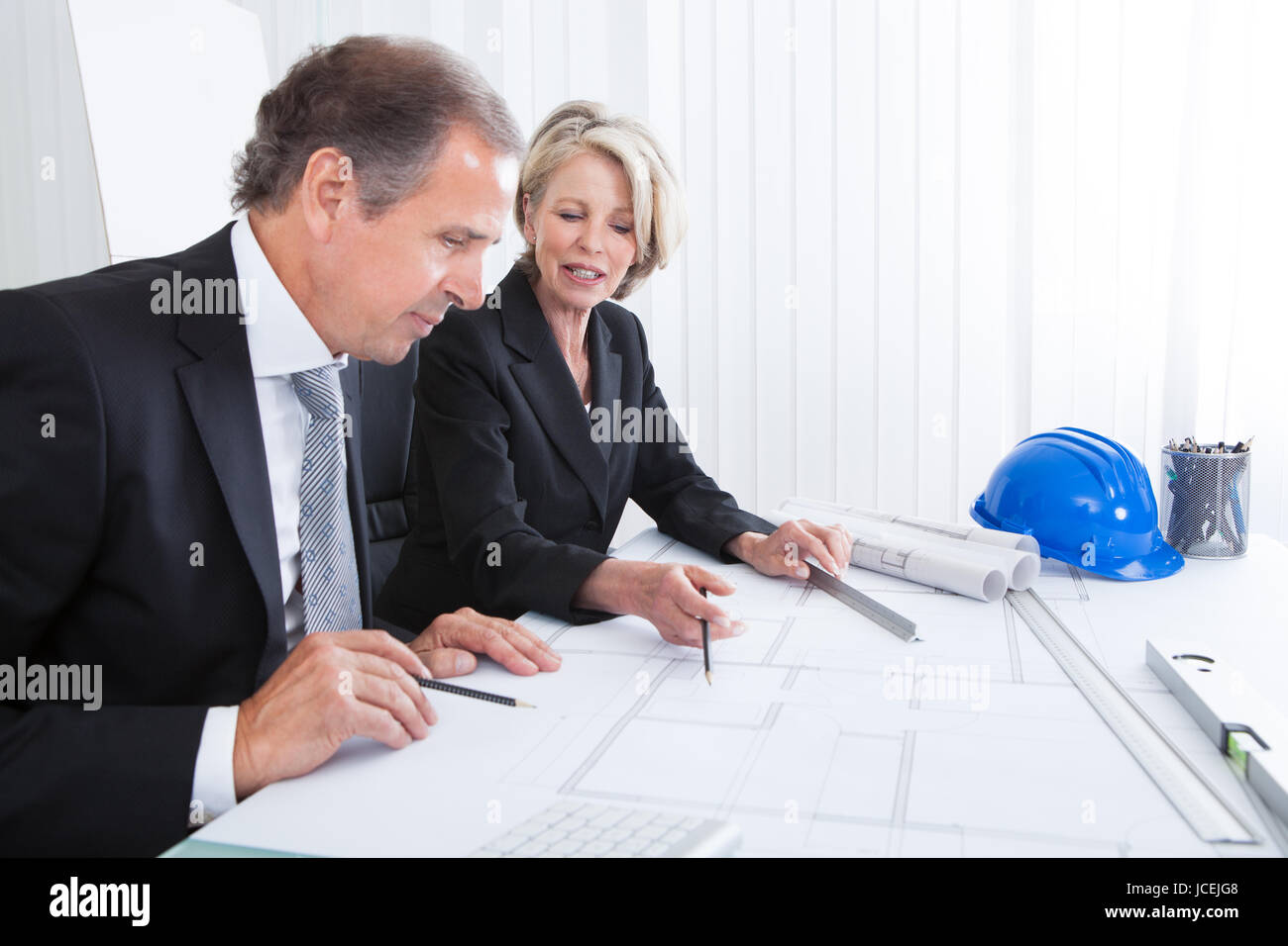 Mature Engineers Looking At Plans Sitting At A Table Stock Photo - Alamy