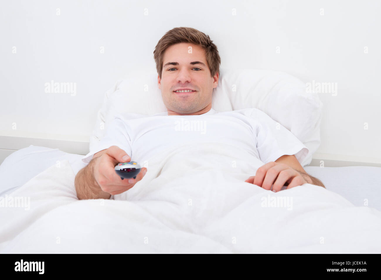 Happy Young Man Lying On Bed Watching Television Stock Photo - Alamy