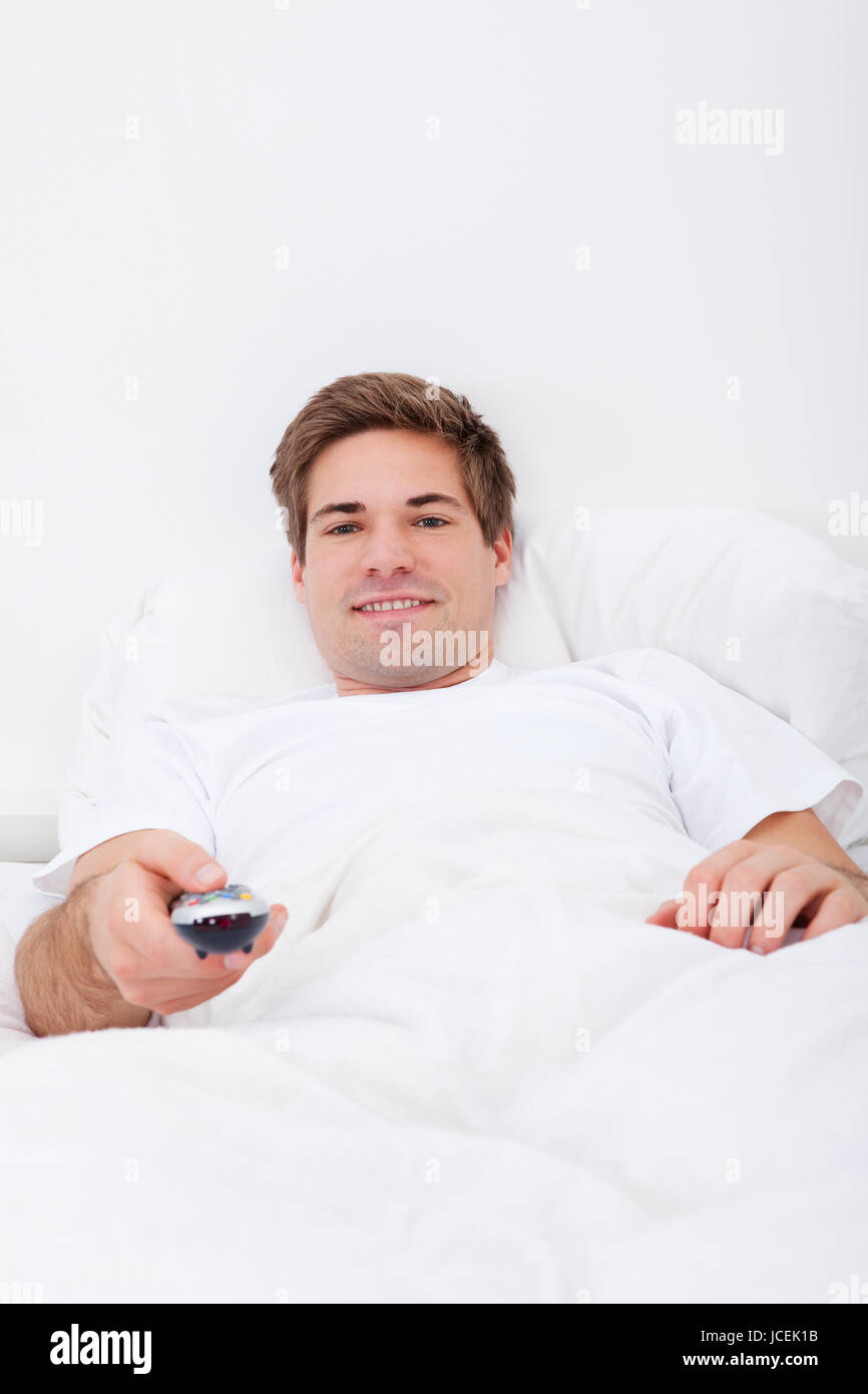 Happy Young Man Lying On Bed Watching Television Stock Photo - Alamy