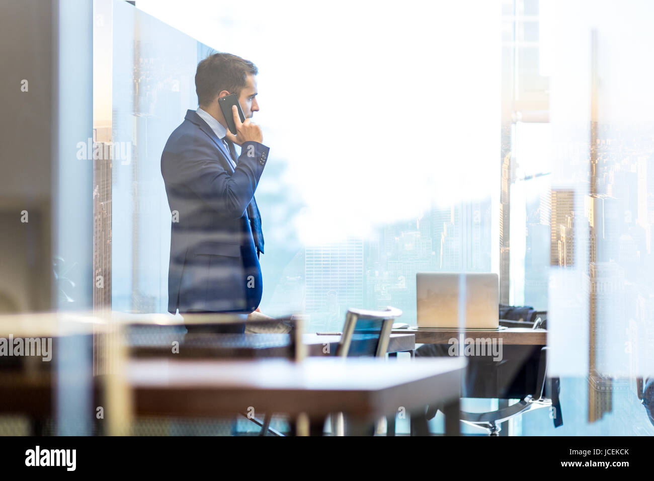 Businessman talking on a mobile phone while looking through modern ...