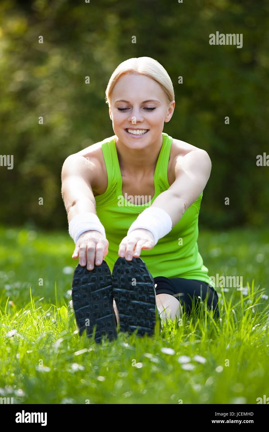 Fit blonde stretching on grass hi-res stock photography and images - Alamy