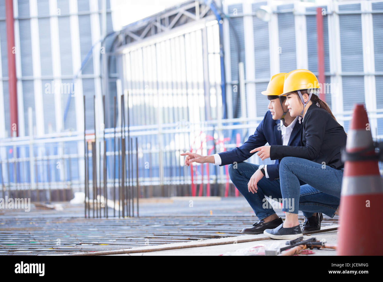 Two architects squatting at construction site Stock Photo - Alamy